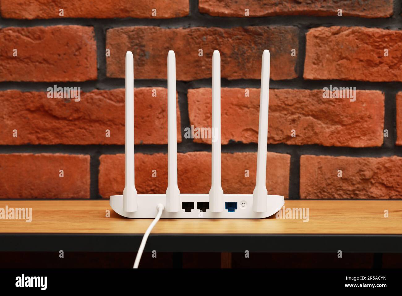 New white Wi-Fi router on wooden table near brick wall Stock Photo - Alamy