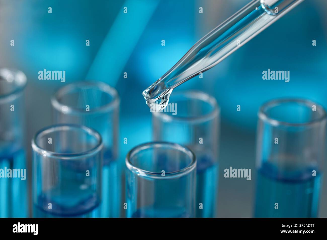 Dripping liquid from pipette into test tube in laboratory, closeup ...