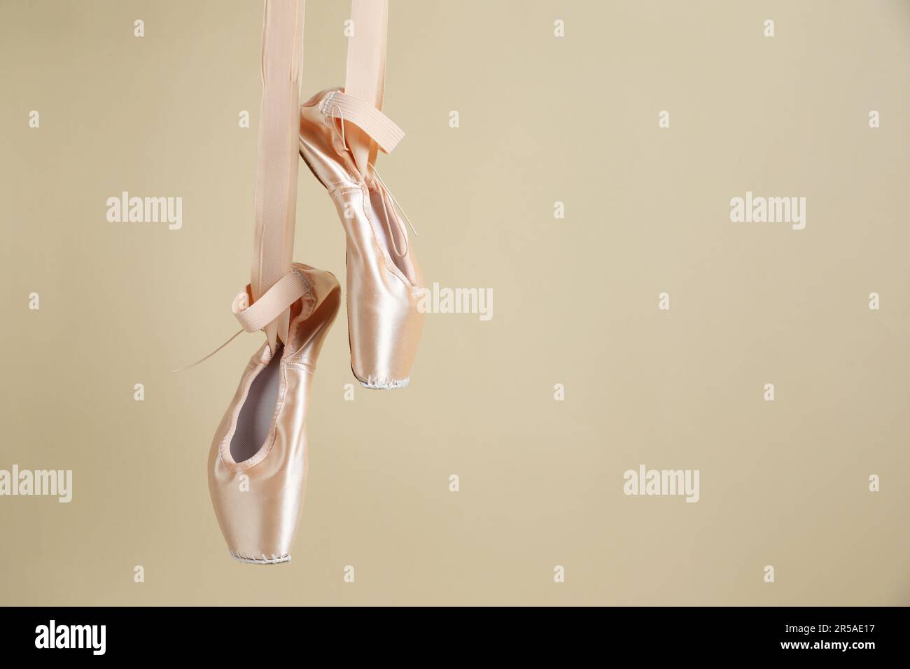 Ballet shoes. Elegant pointes hanging on beige background. Space for ...