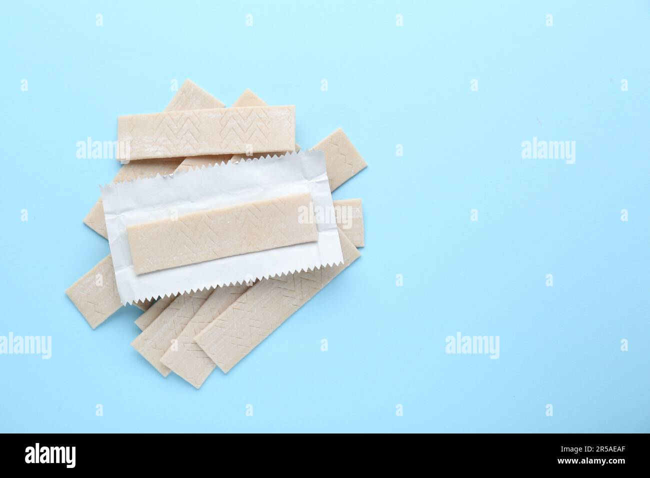 Many sticks of tasty chewing gum on light blue background, flat lay ...
