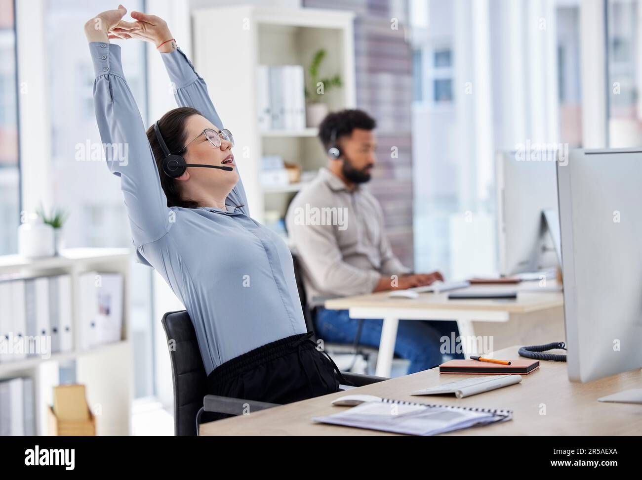 Customer service, woman with headset and stretching her arms at her ...