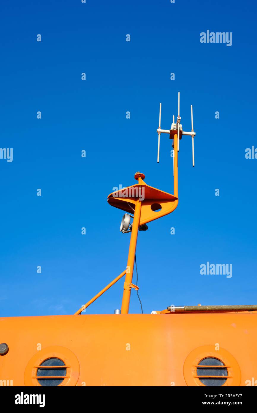 Communication mast on a bright orange Lifeboat or rescue boat against a ...