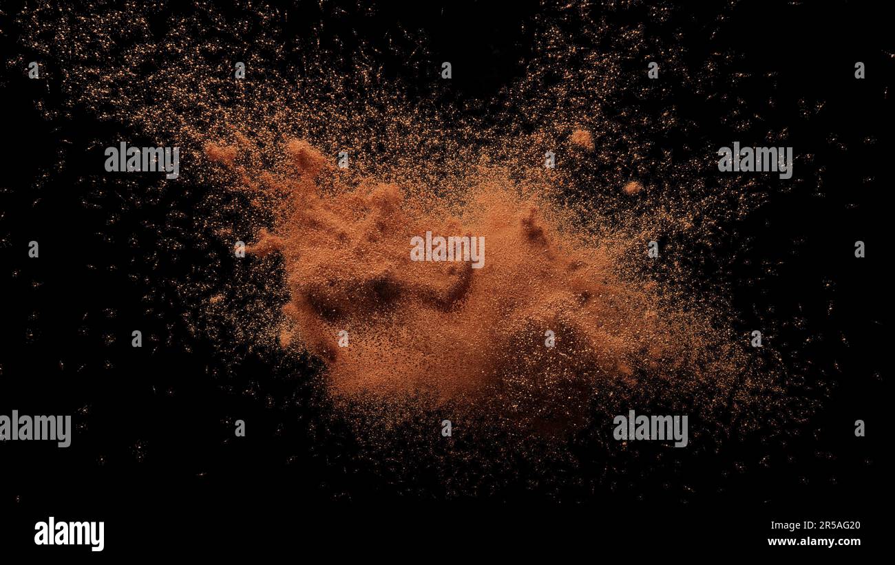 orange particles flying, colored powder in the air, isolated on black ...