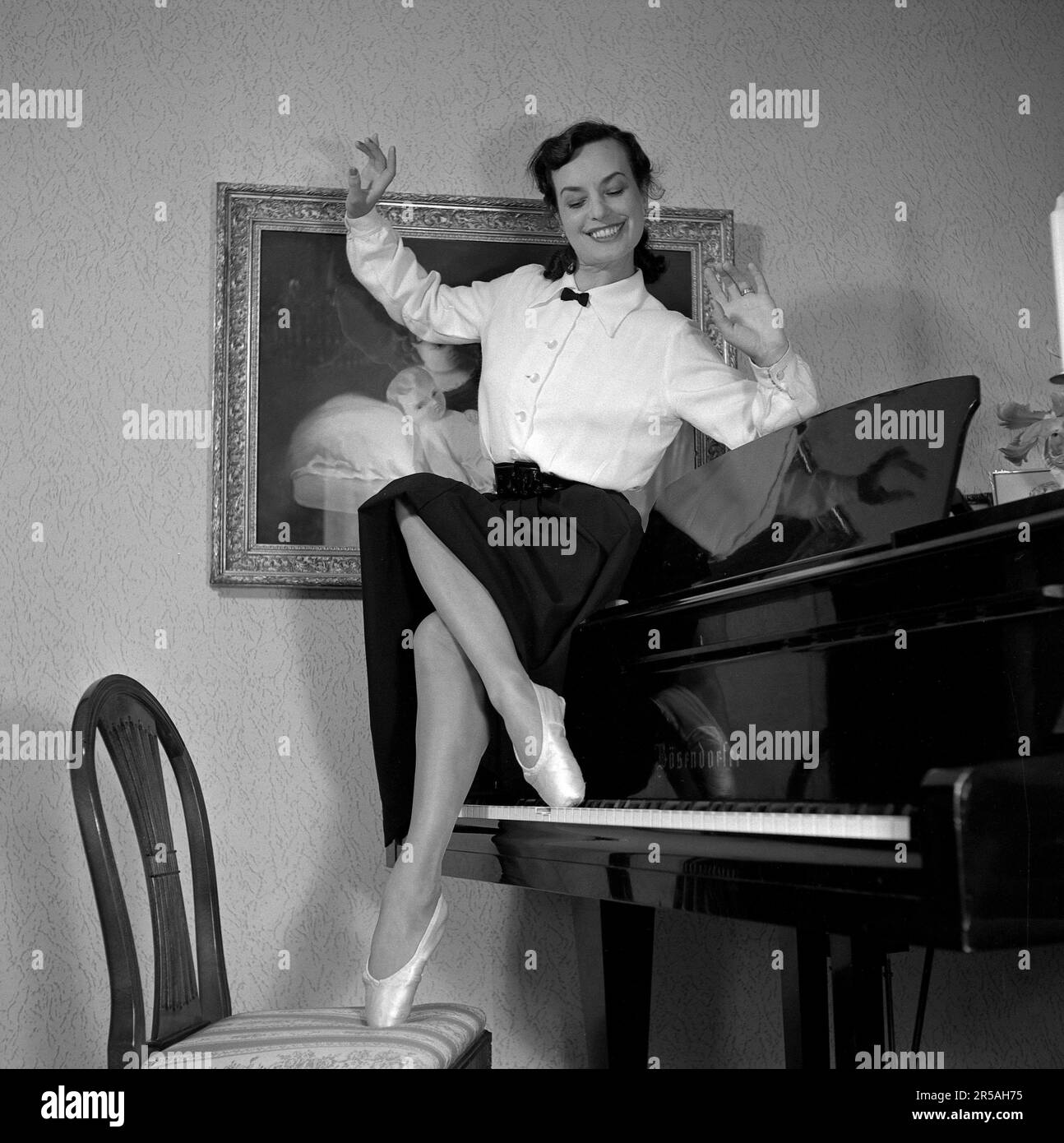 Ballerina in the 1950s. A young ballerina is sitting on a grand piano ...