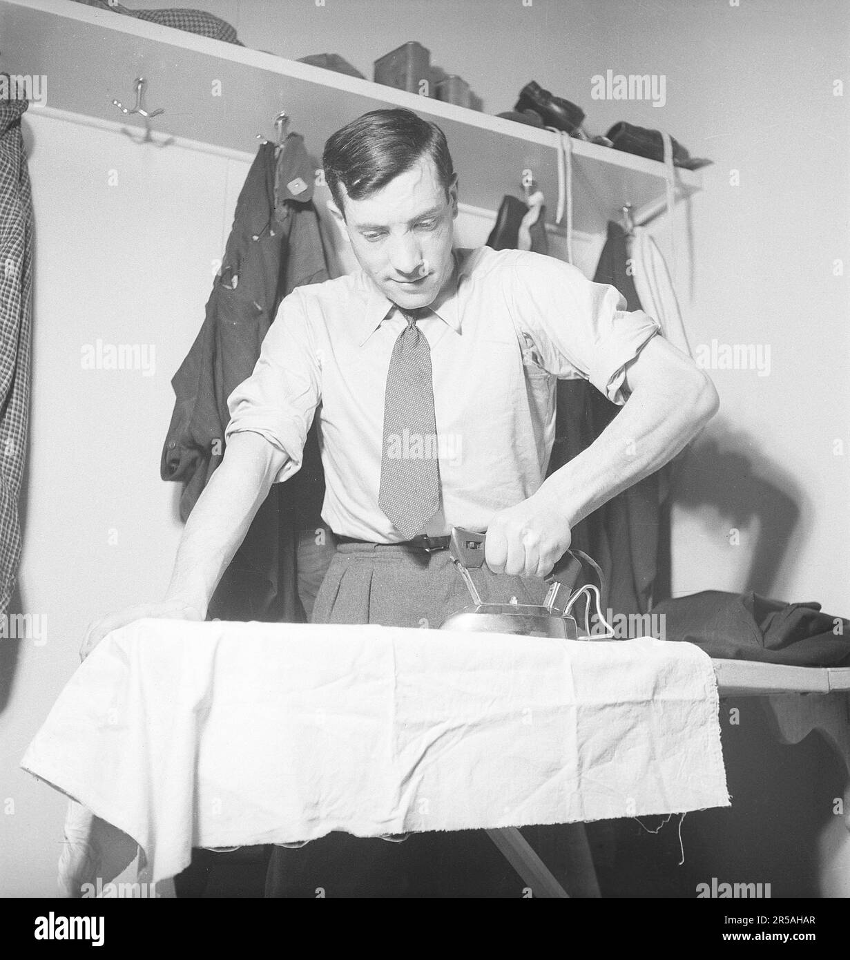 A man is ironing something on an ironboard. Sweden 1948 Kristoffersson ...