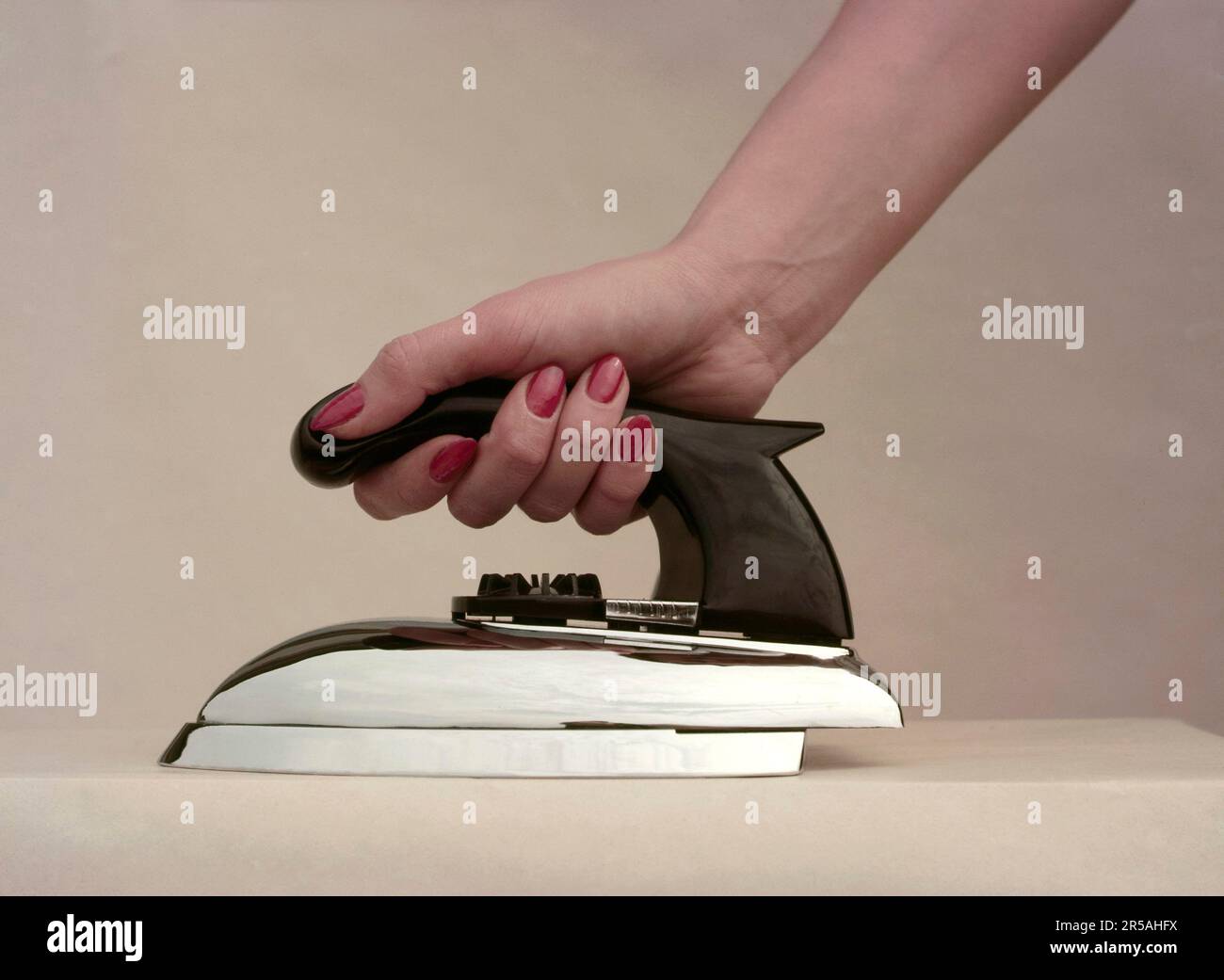 Ironing in the 1960s. Detail of a women's hand holding an electrical ...