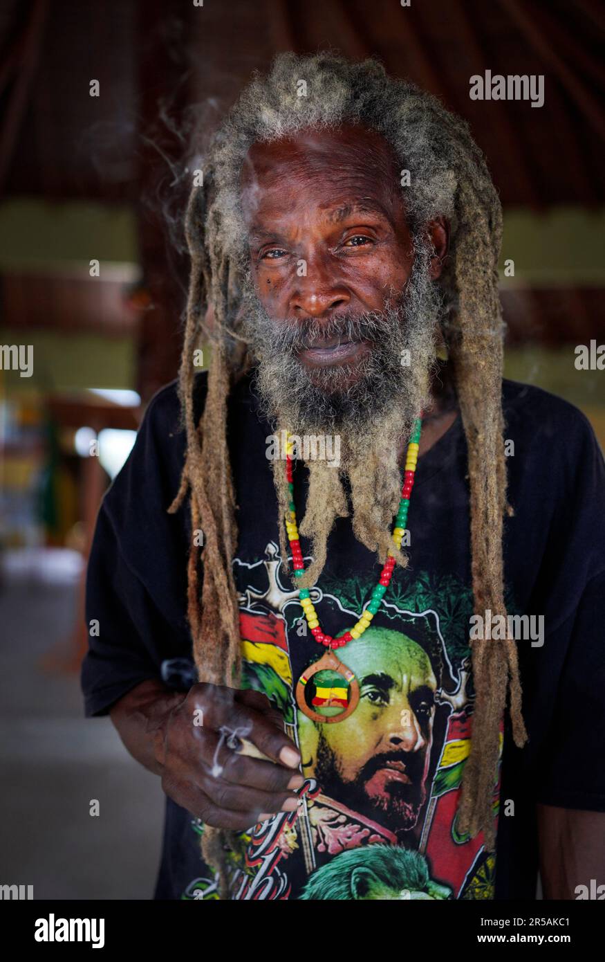 Rastafari member Jahwanzer John stands for a portrait while smoking a ...
