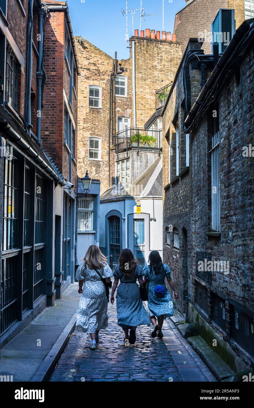 Three women walking in Newman Passage, a narrow alleyway in Fitzrovia ...