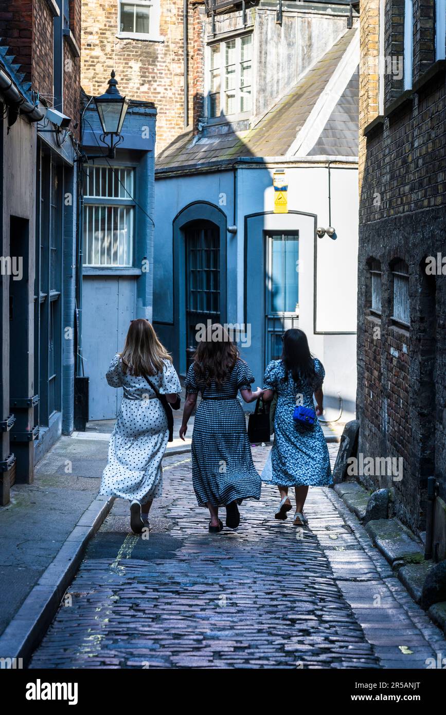 Three women walking in Newman Passage, a narrow alleyway in Fitzrovia ...