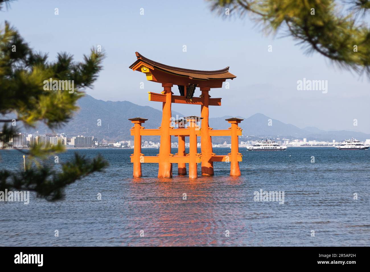A large wooden Torii gate floating in a tranquil body of water ...