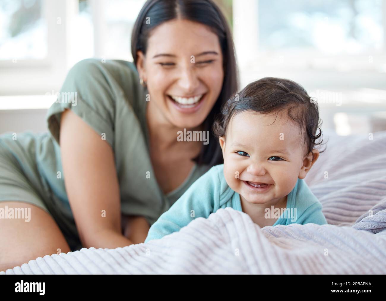 Mother, laughing baby and play on bed in home for love, care and ...