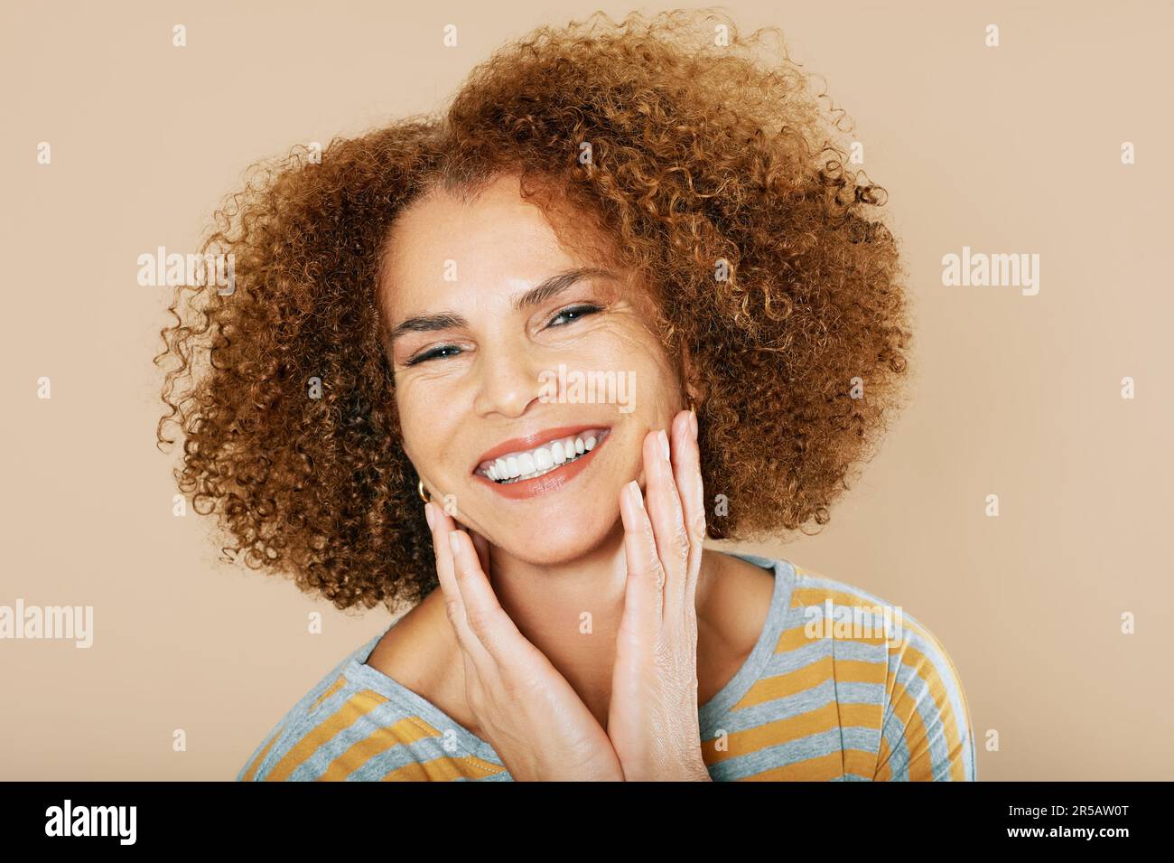 Close up studio portrait of beautiful middle age woman with curly hair, 50 - 55 year old lady ...