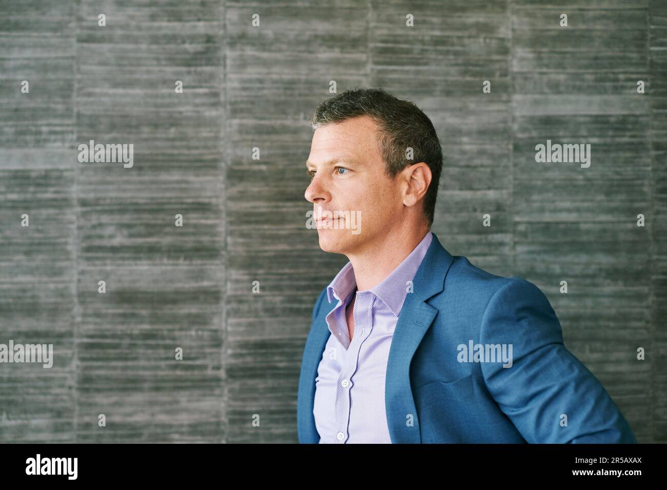 Portrait of mature 40 year old man posing bext to grey wall background ...