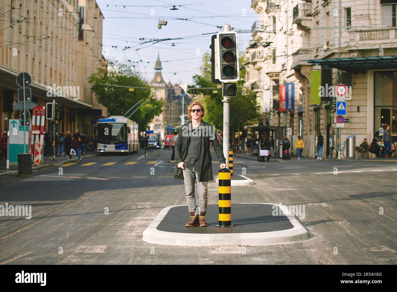 Outdoor portrait of handsome young man posing in the middle of the road ...