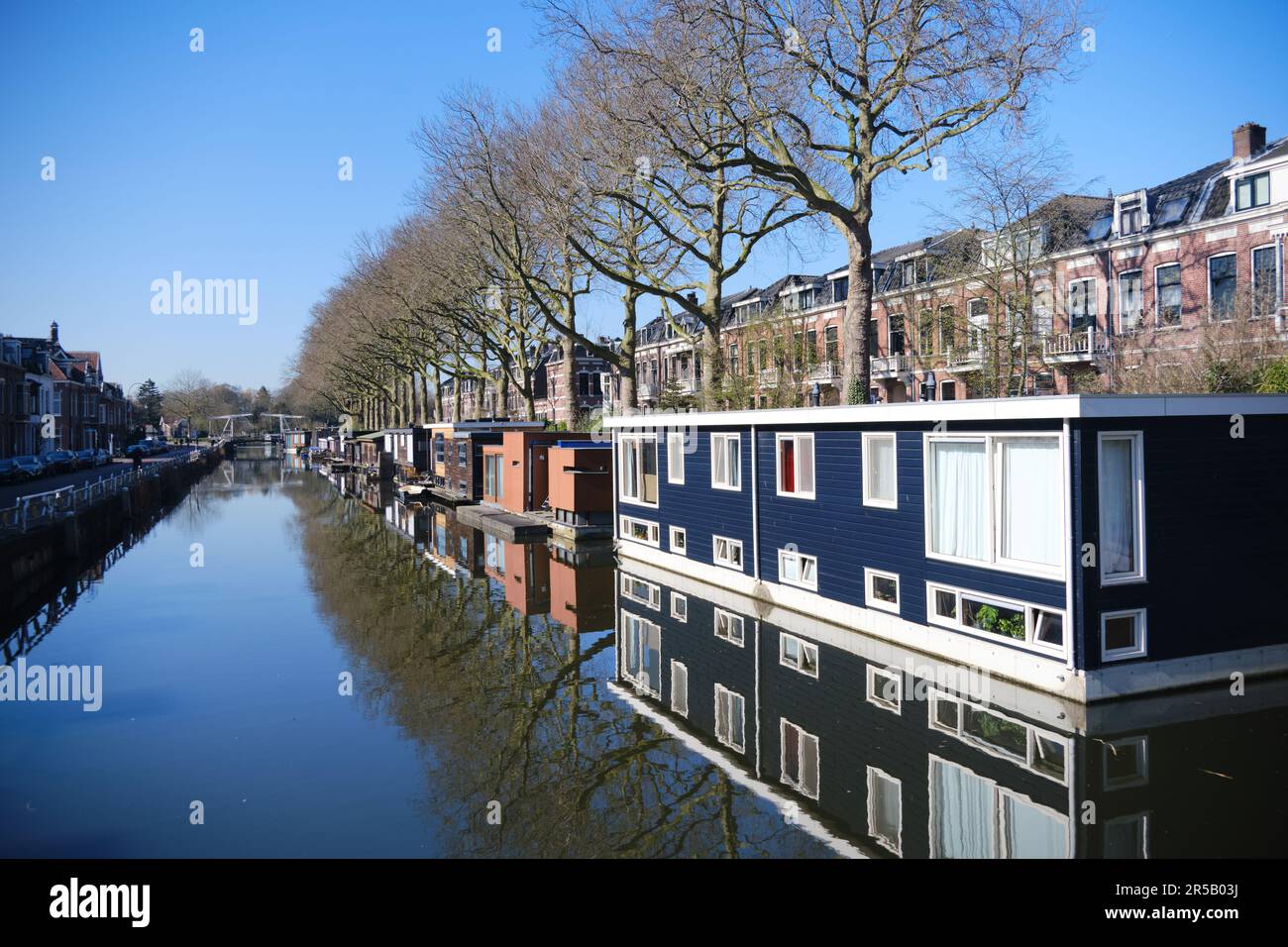 Canal quay covered in bright sunshine and floating home boats on the ...