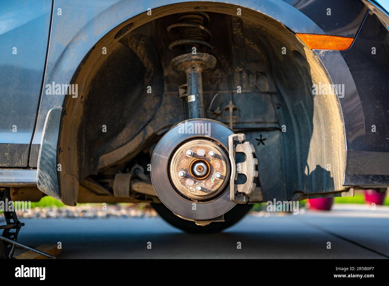 Wheel well of a vehicle lifted with a tire jack. Rusted hub and strut ...
