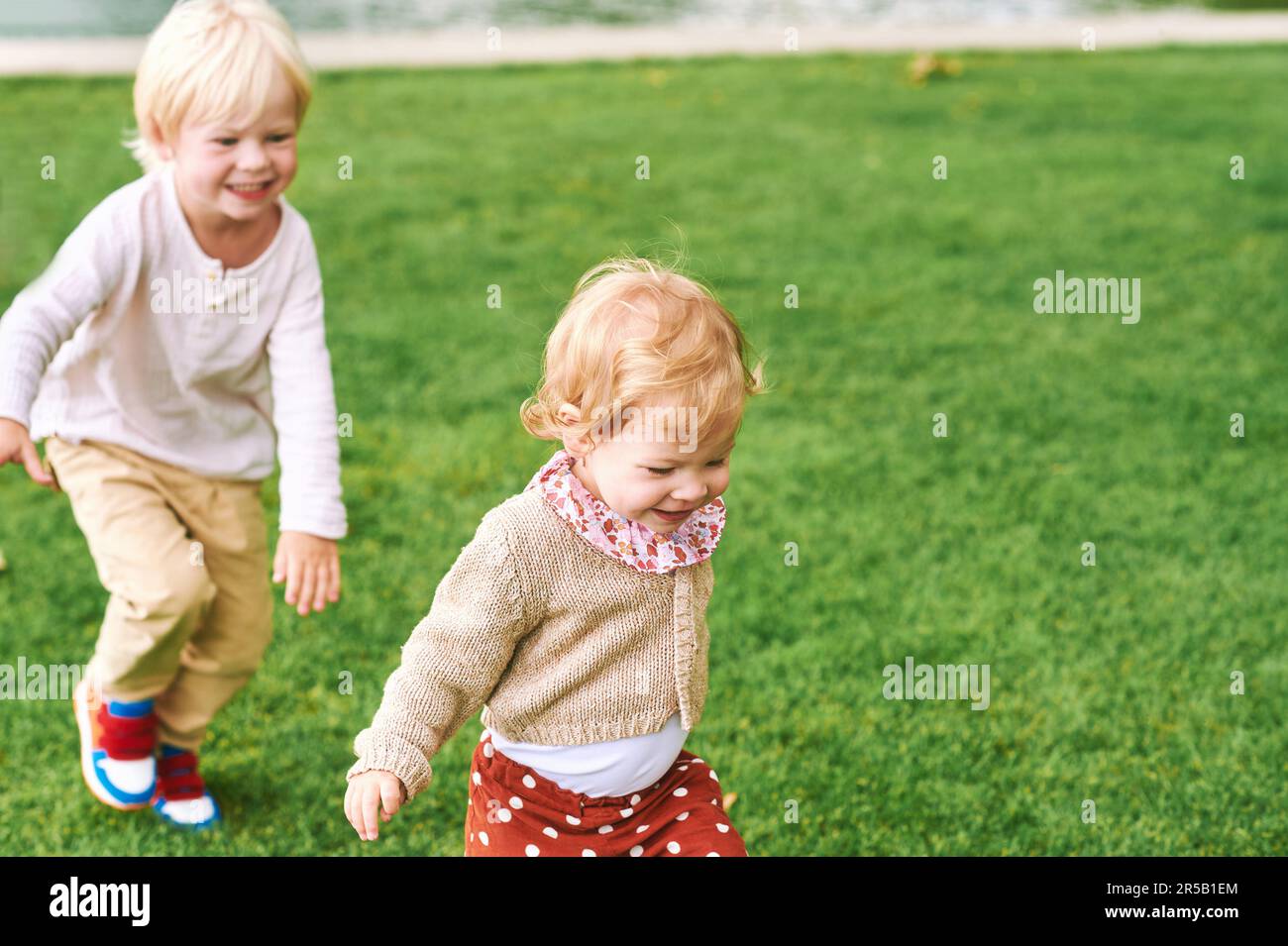 Outdoor portrait of adorable happy children playing together, running ...