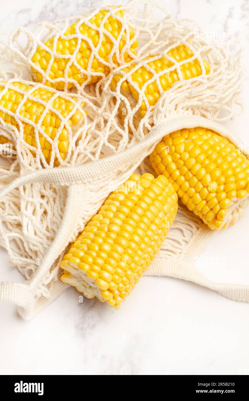 Five pieces of corn in a cotton mesh bag on a white marble kitchen ...