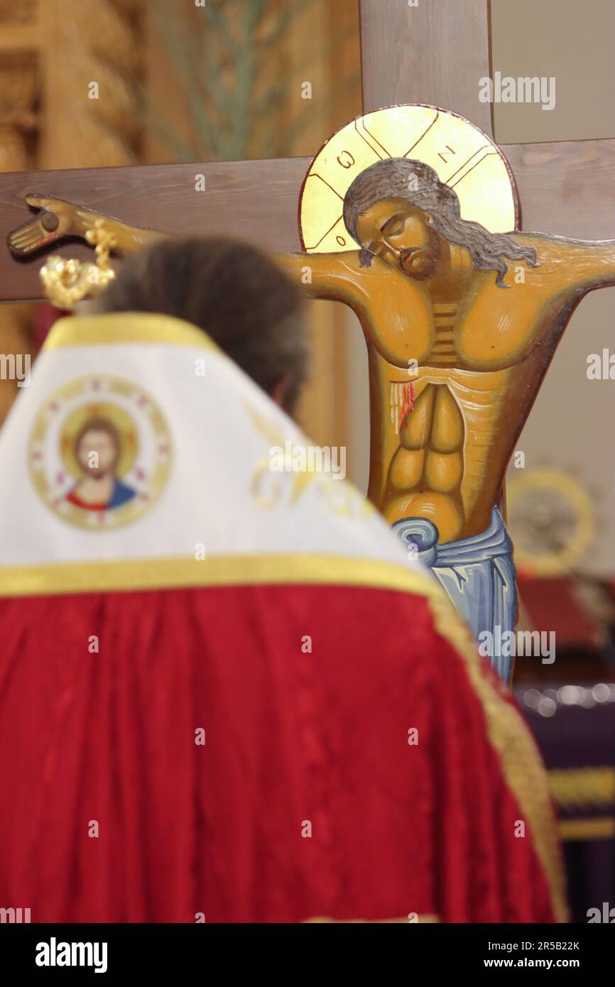 A priest standing in front of a statue depicting Jesus on the cross in ...