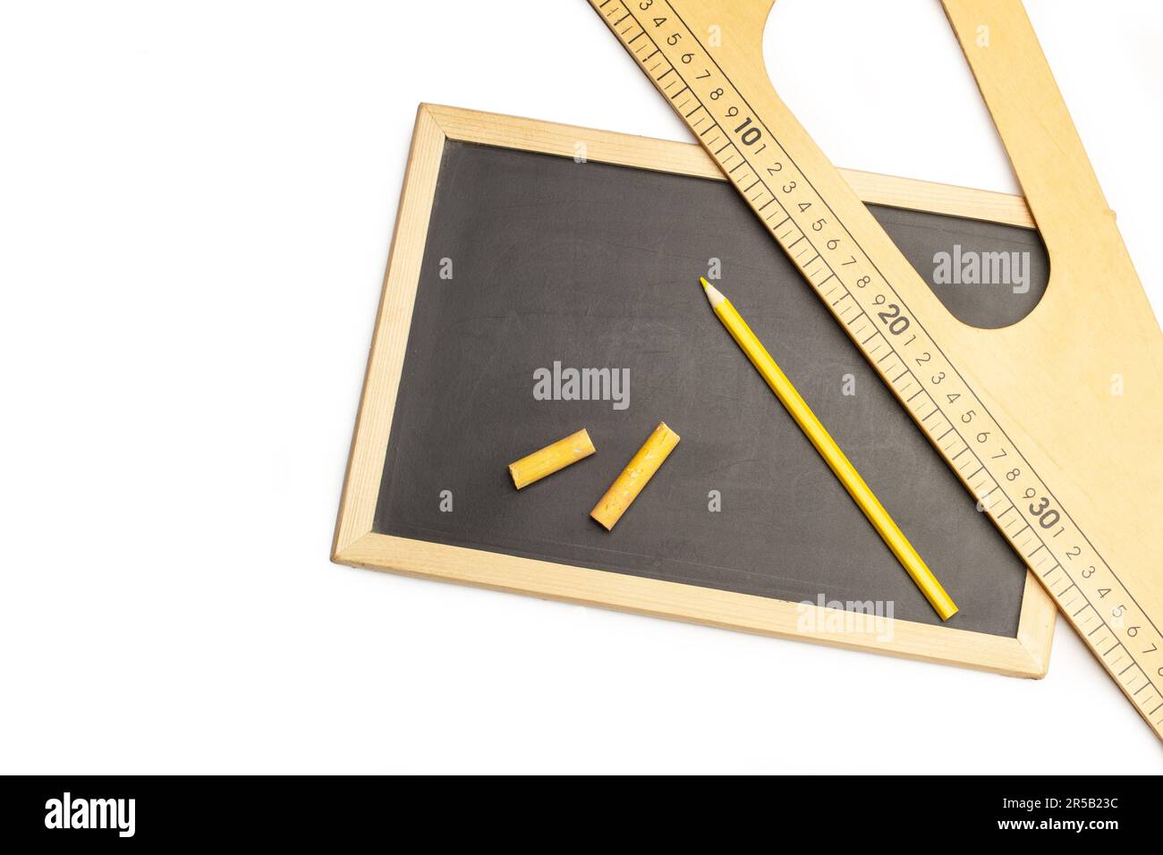 Wooden triangle ruler, a yellow pencil and chalks on a blackboard and ...