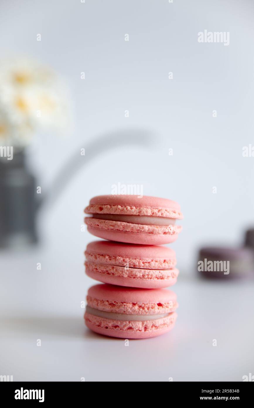 Stack of three pink macarons in the back and one bitten pink macaron in ...