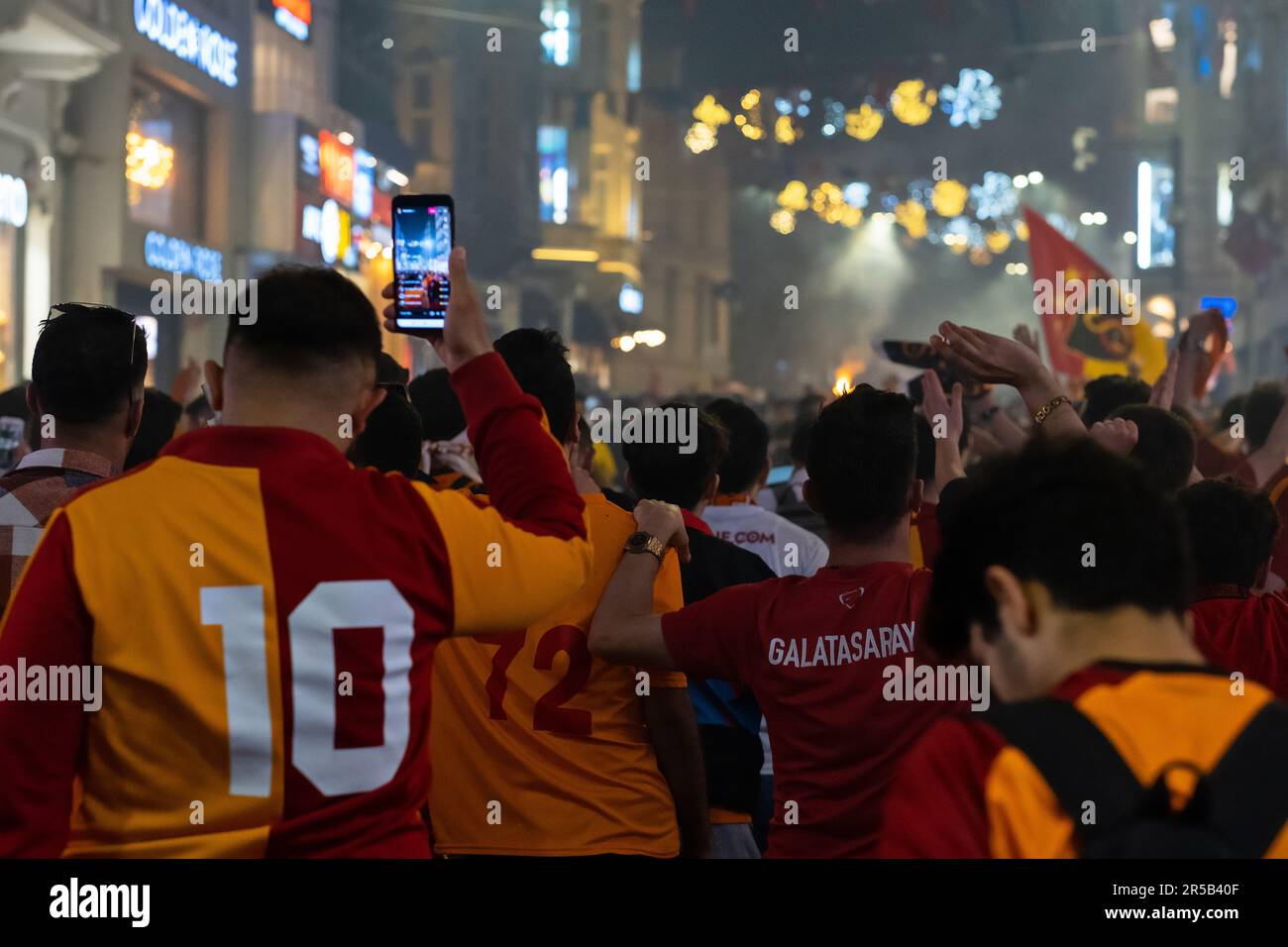 Group of fans with Galatasaray shirts their backs turned, celebration ...