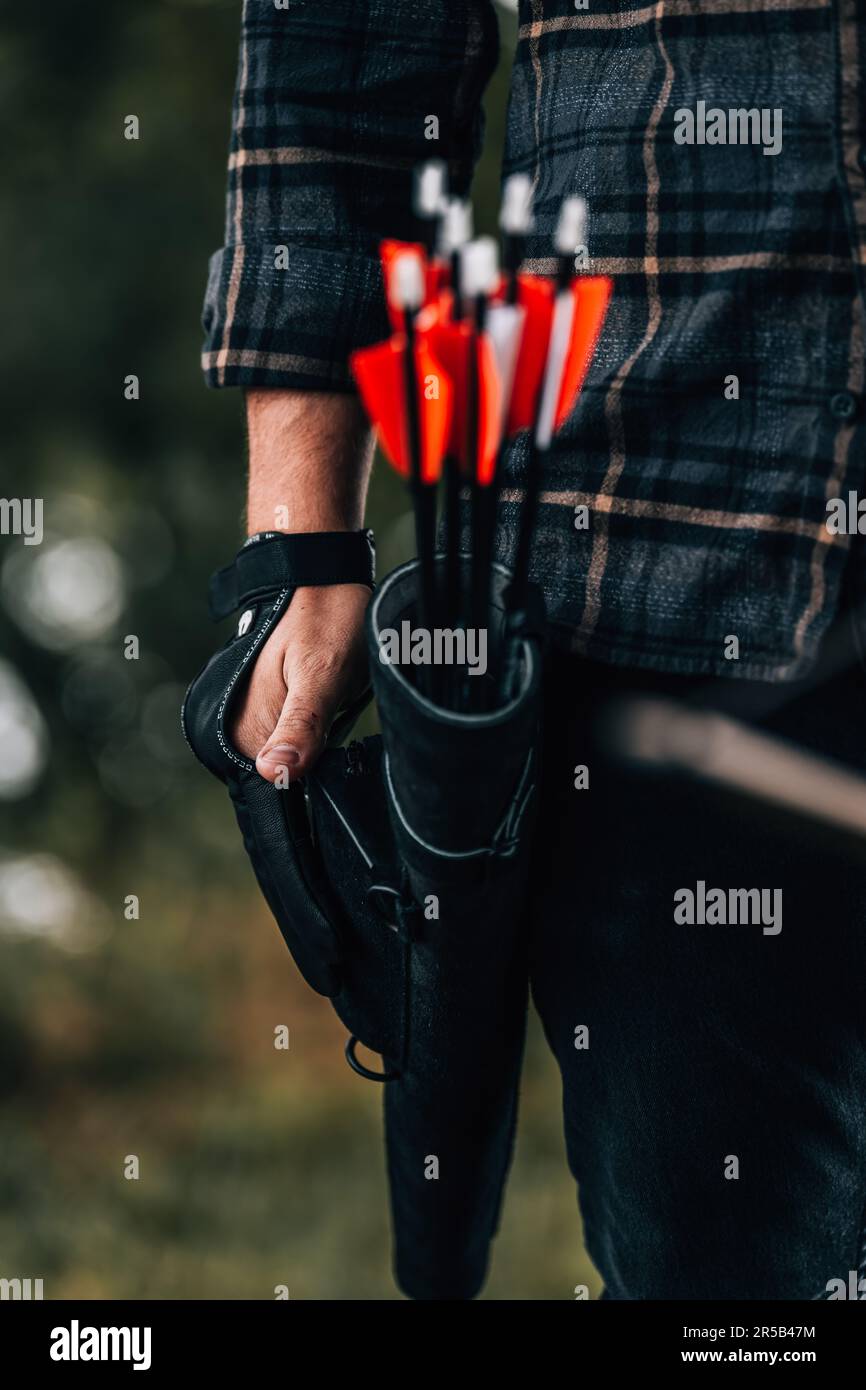 A young man stands outdoors, with a quiver of arrows and bow slung ...