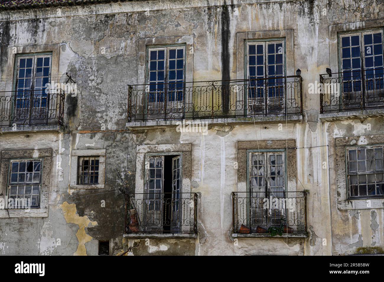 An aged and deteriorated building featuring multiple windows and doors ...