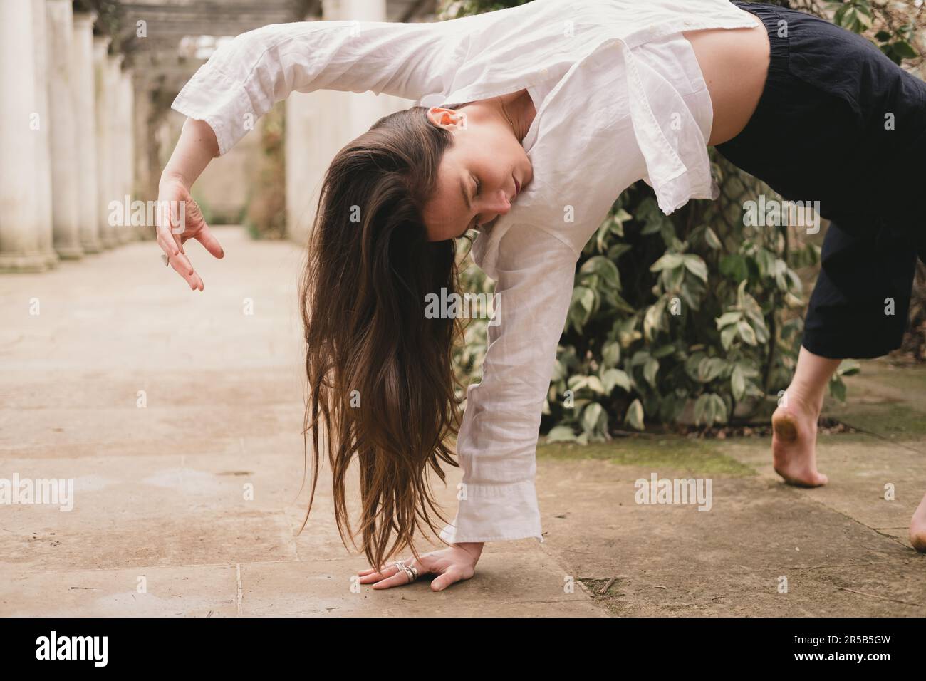 A female yogi in wild thing pose in a dreamlike leafy terrace of a ...