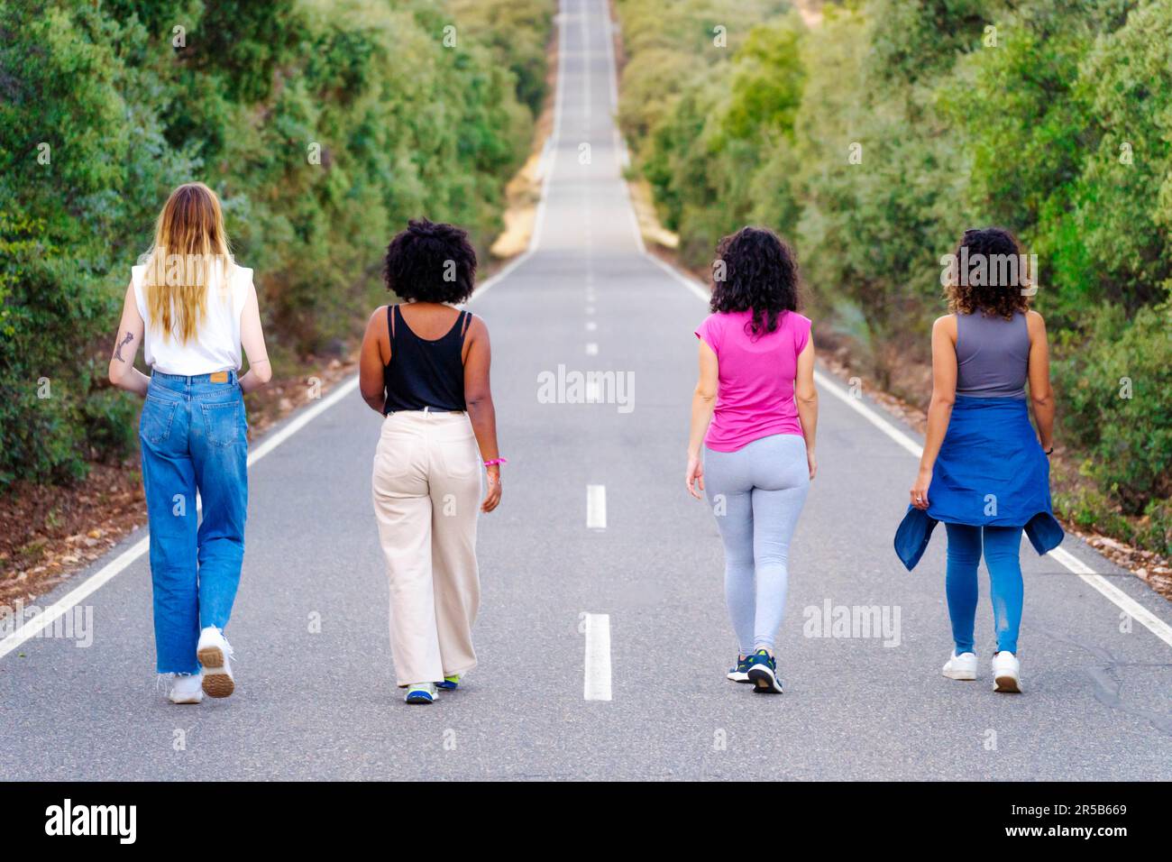 Three young women walking side by side along a rural road, taking ...