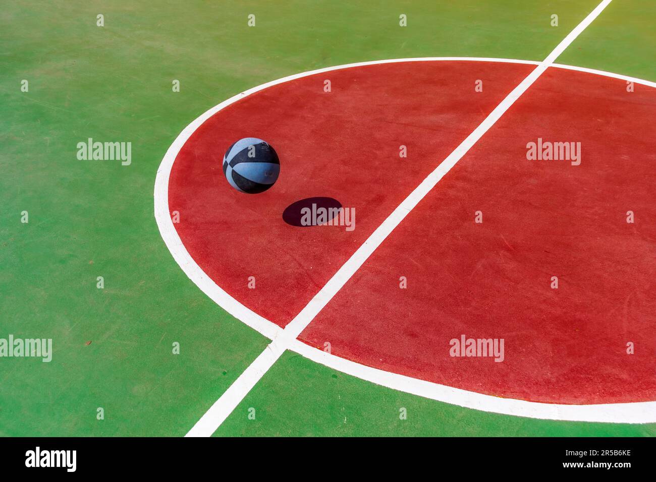 Red and green basketball court with a gray striped ball frozen in full ...