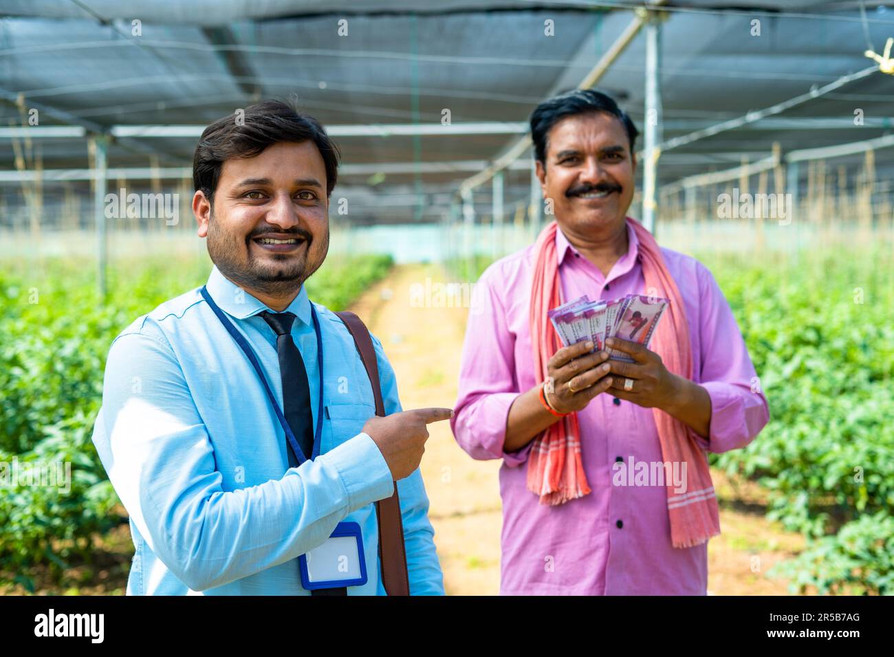 Happy Indian Banker Pointing Finger To Farmer With Money At Greenhouse Concept Of Financial