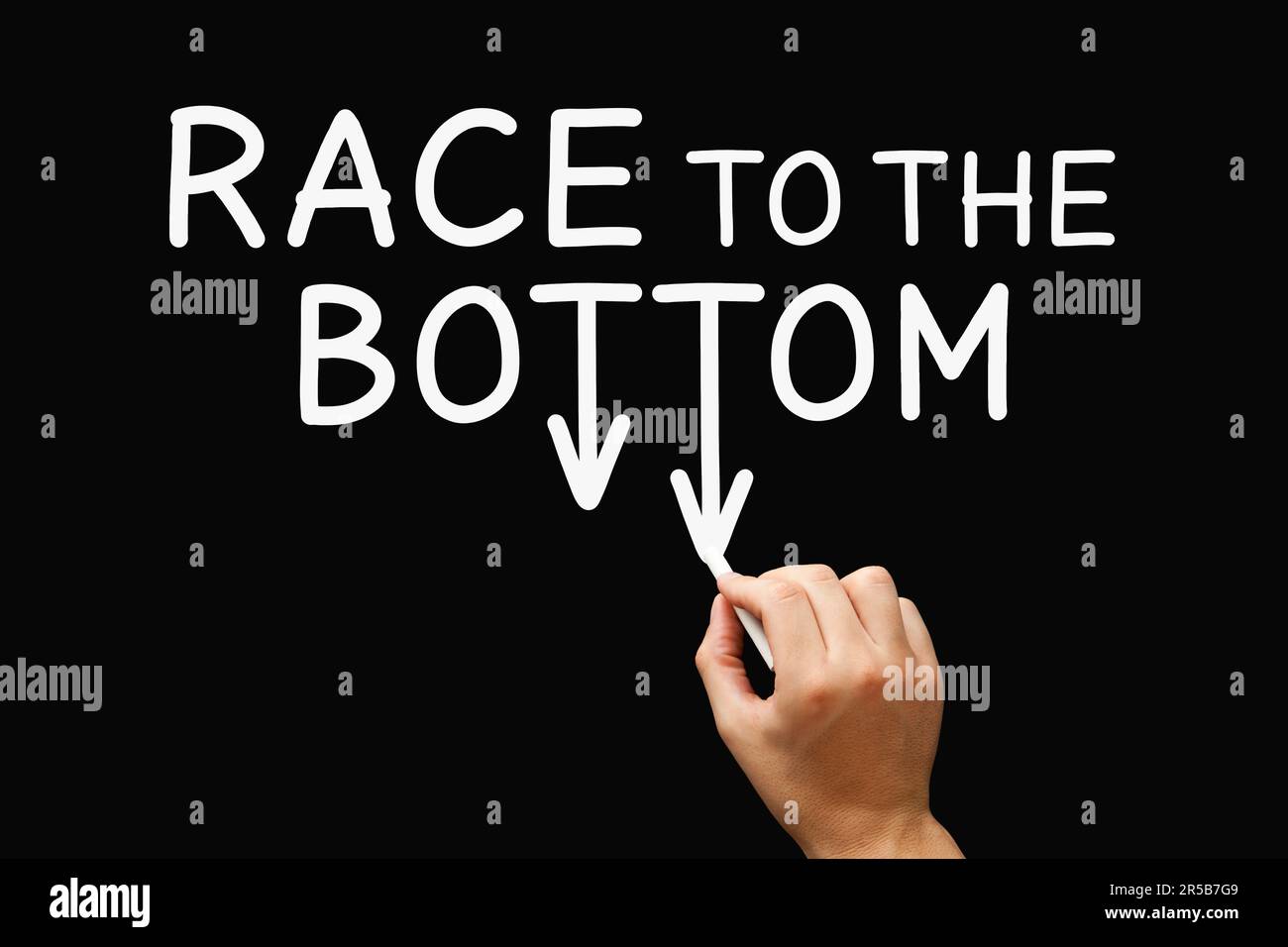 Hand writing the phrase Race to the Bottom with white on black background. Concept about dumping ...
