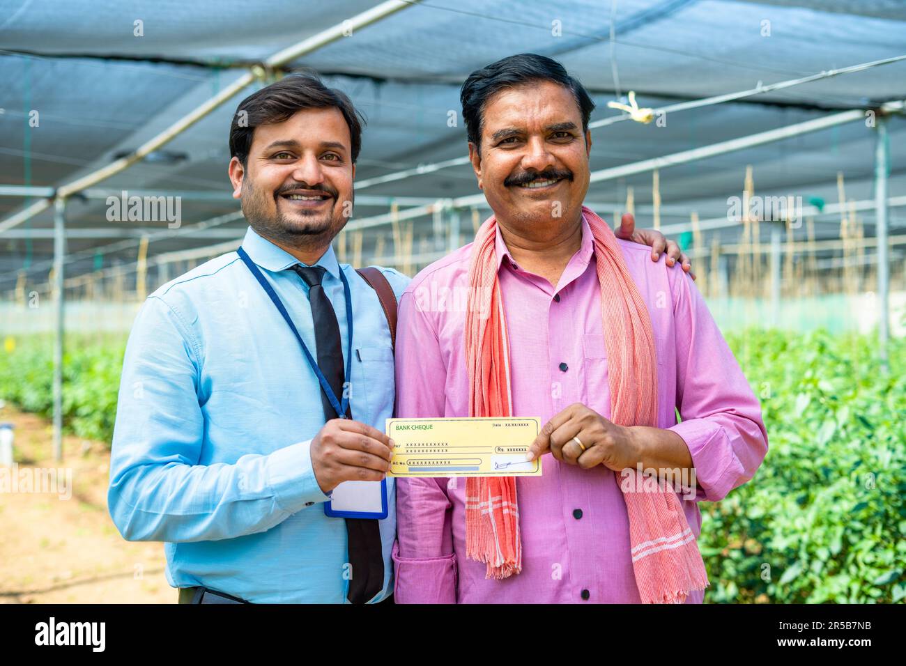 Happy Indian village farmer receiving cheque from banker by looking at ...