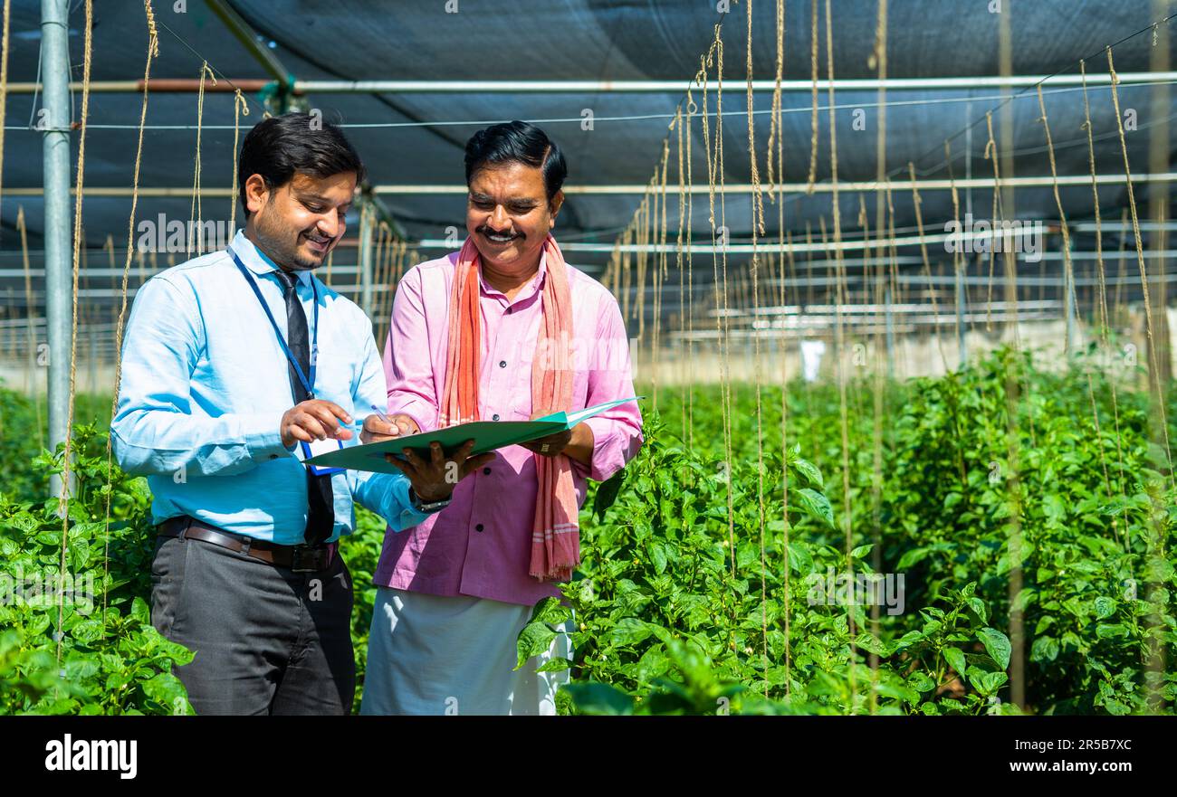 Happy indian bank officer taking sign from farmer to loan approval ...