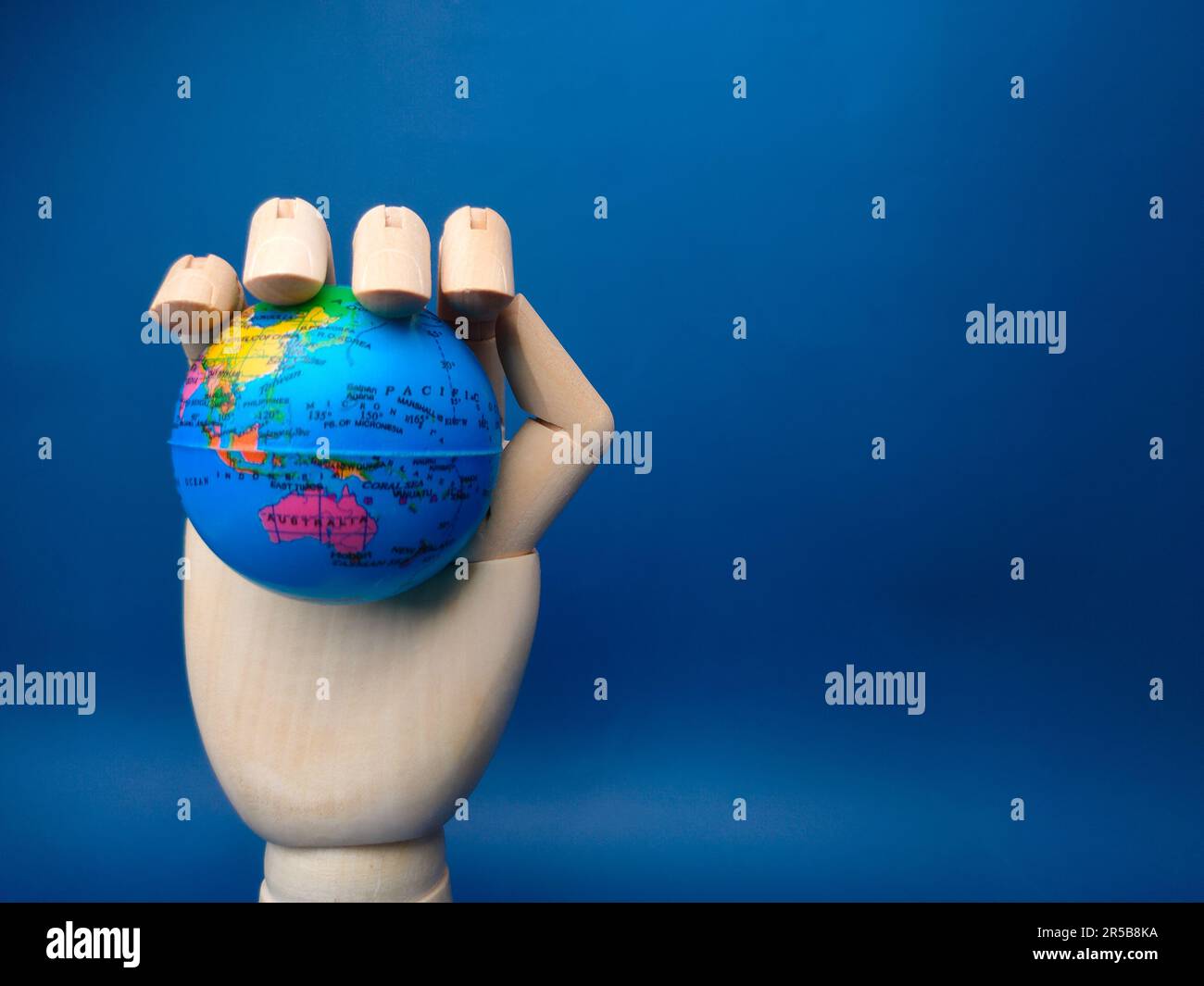 A wooden hand puppet with a blue globe held up in the air Stock Photo ...