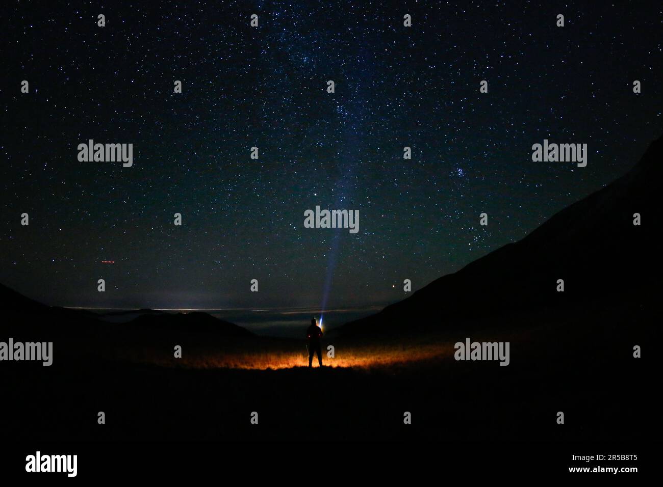 A human standing at the end of a road, captivated by the starry night ...