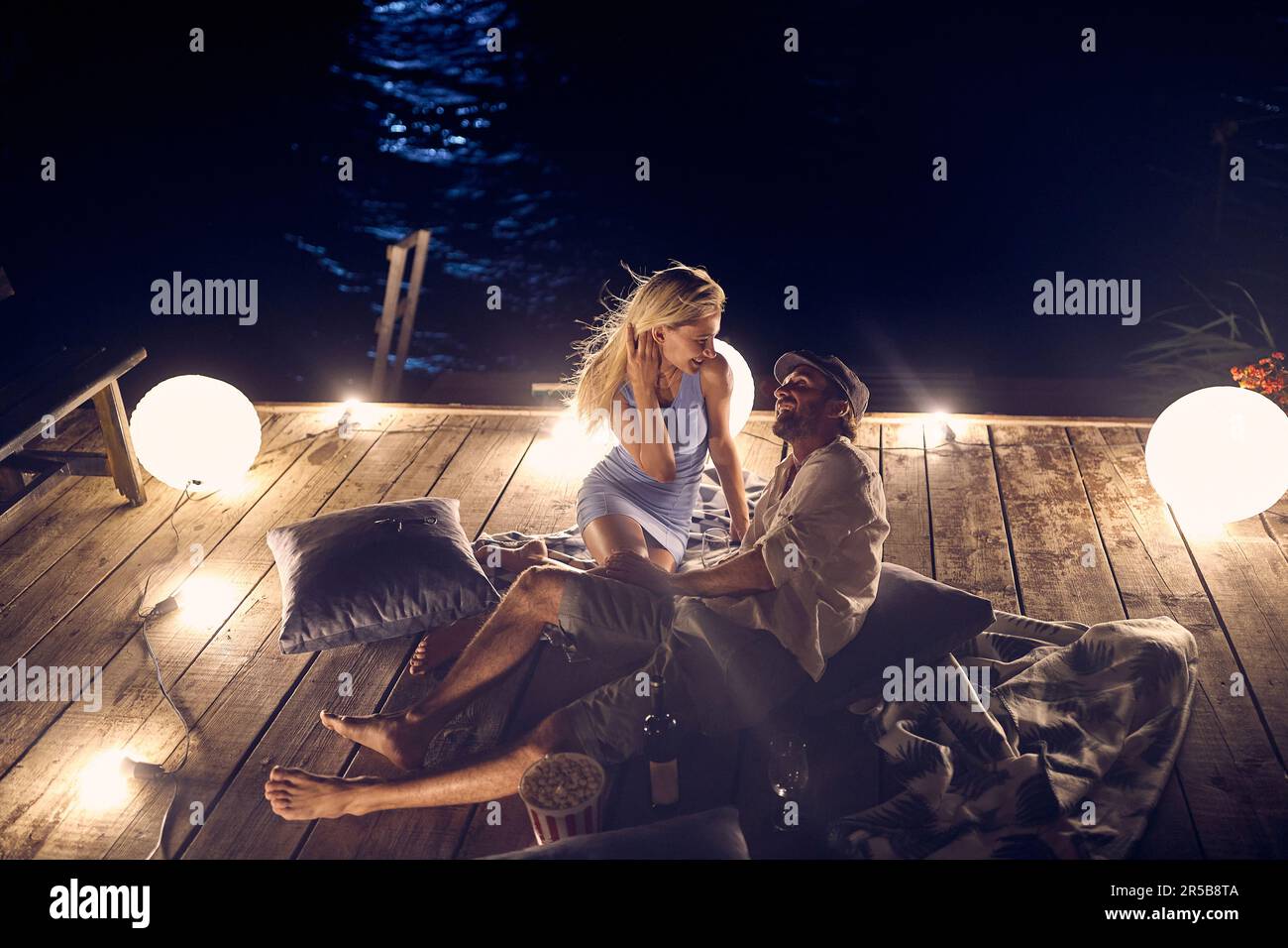 Romantic couple sitting together on a water dock at beautiful moon at ...