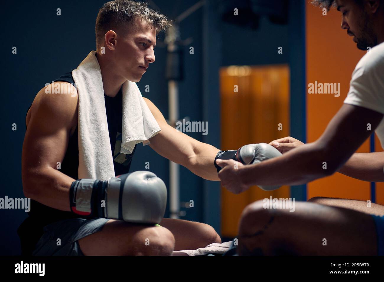 Young boxing player sitting in dressing room preparing for workout ...