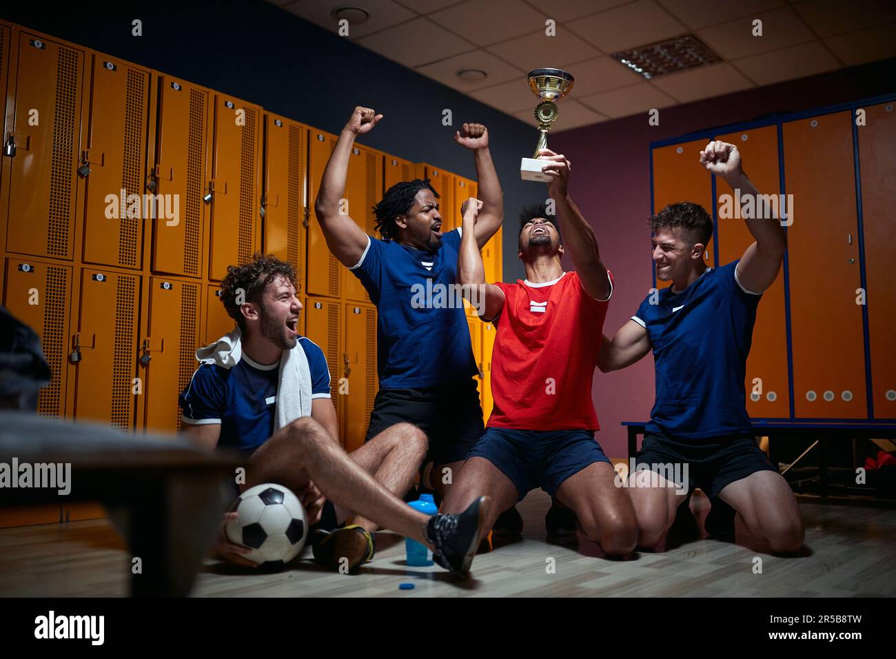 Young team of football players celebrating success with golden trophy ...