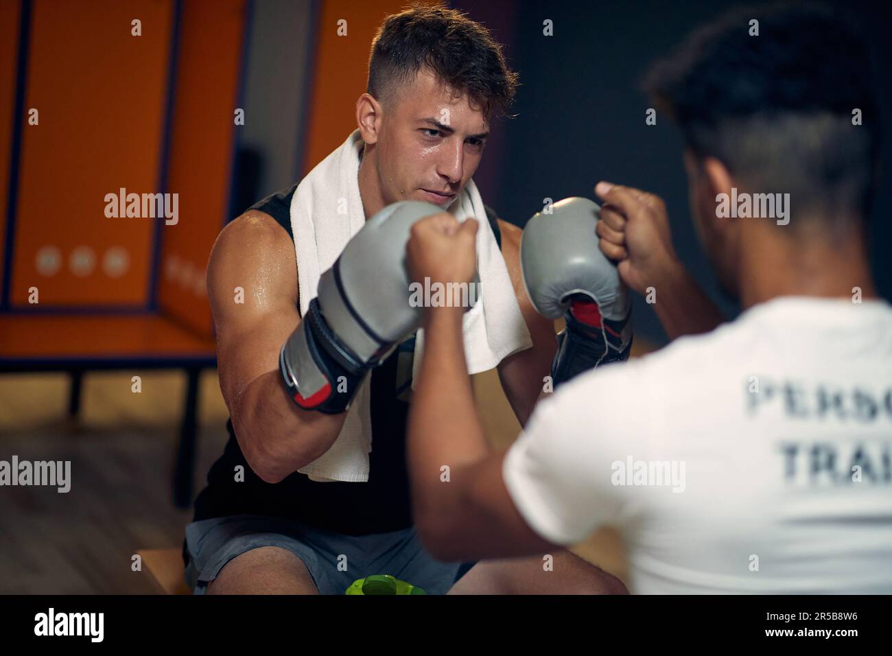 Determined and focused young sweaty boxing player with his coach in ...