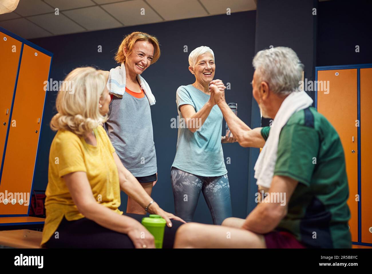 Senior man and woman high fiving in gym locker room, feeling energized ...