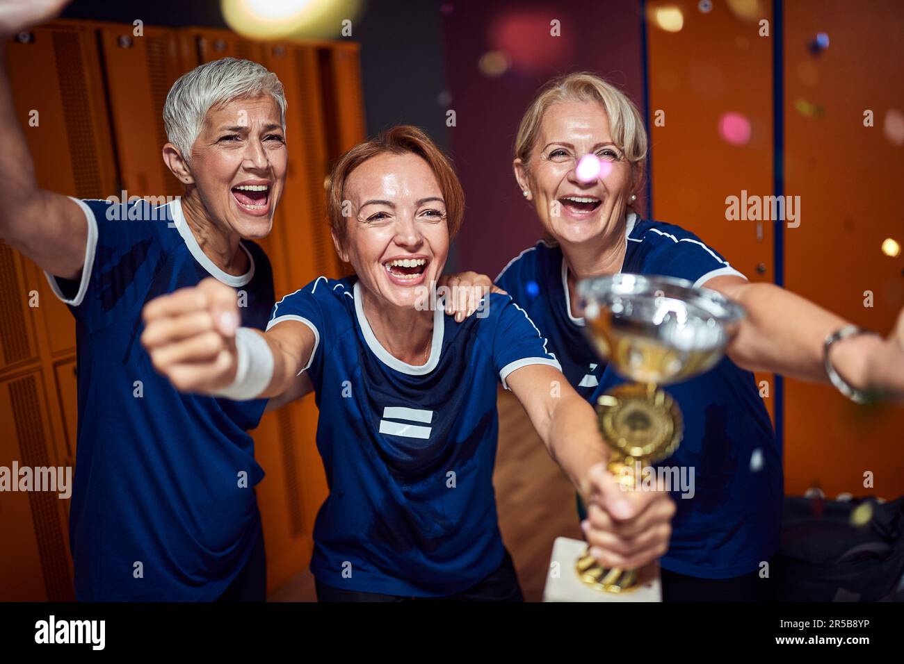 Lovely team of senior and young women celebration win with golden cup ...