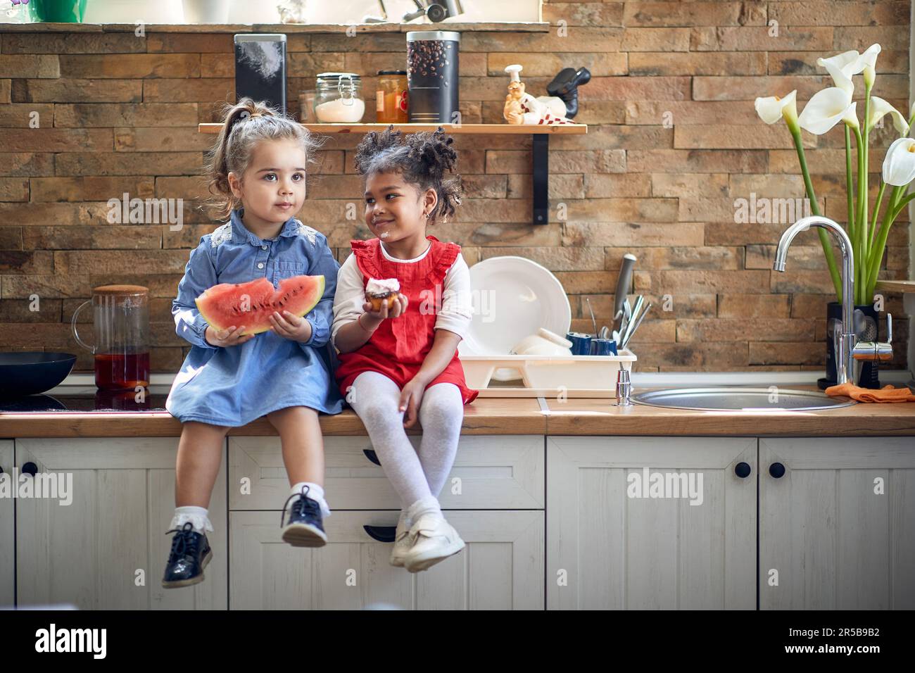 Two young girls come together in the kitchen.One girl takes a joyful ...
