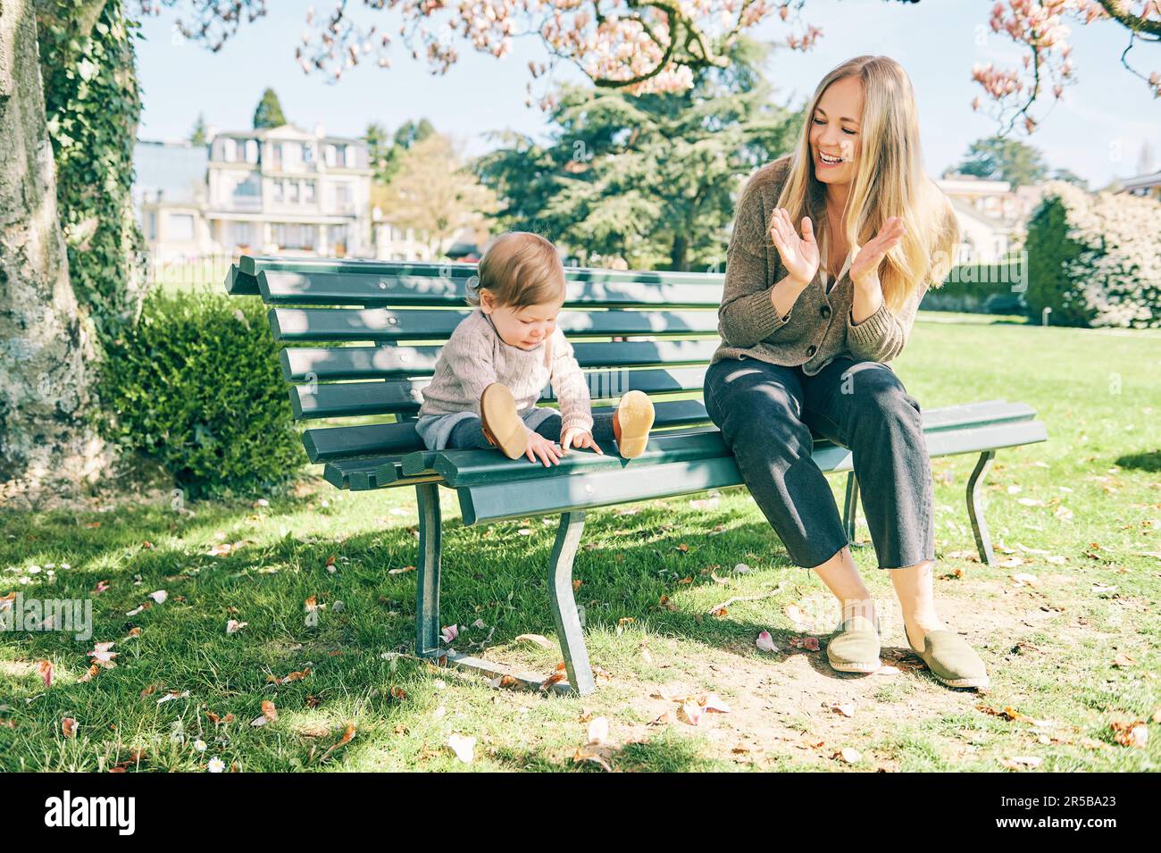 Outdoor portrait of happy young mother playing with adorable baby girl ...