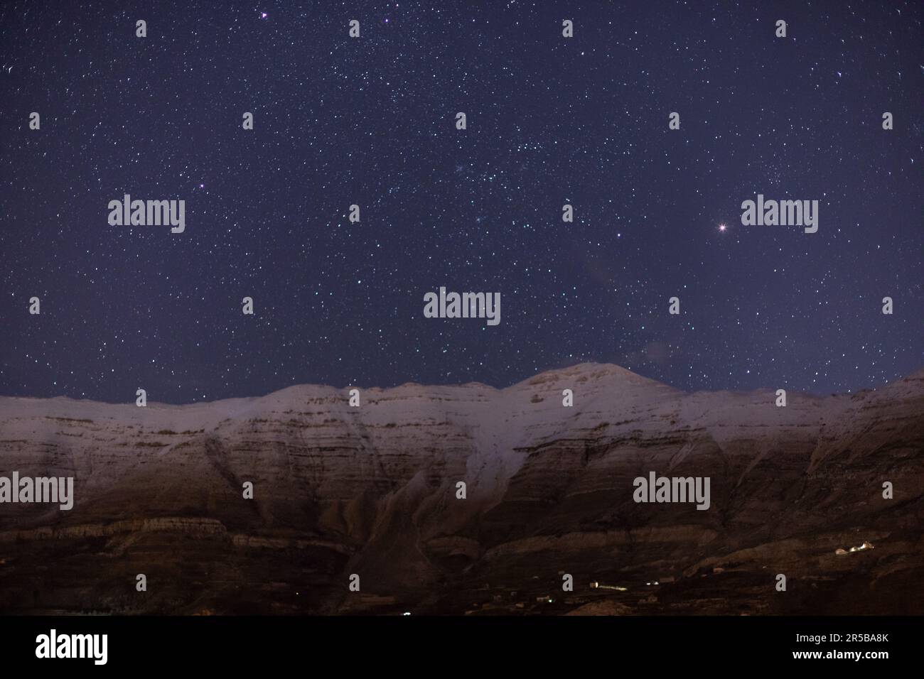 A landscape of snowy hills under a starry sky at night in the ...