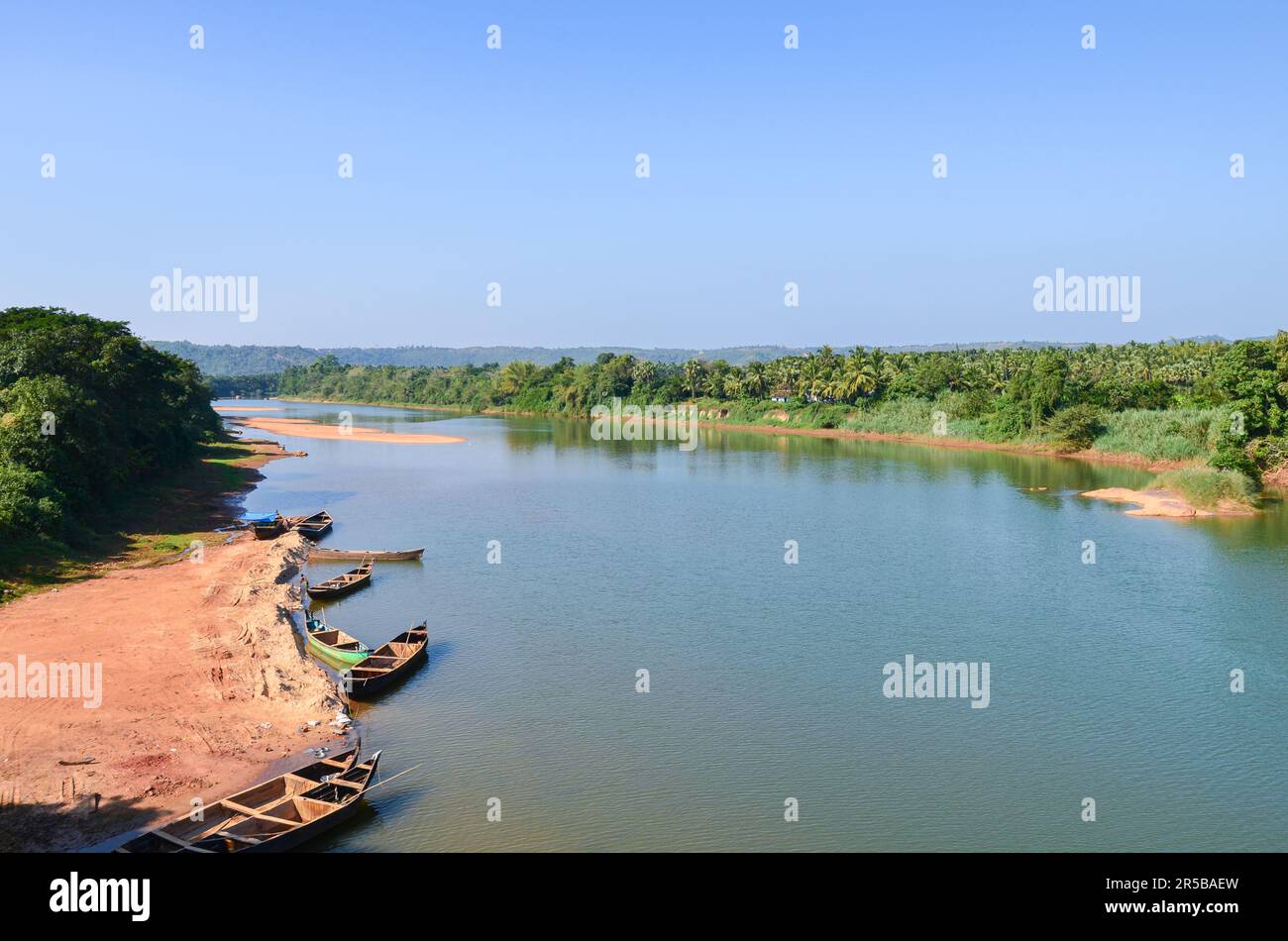 River with lush green river bank and sand mining boats at Polali ...