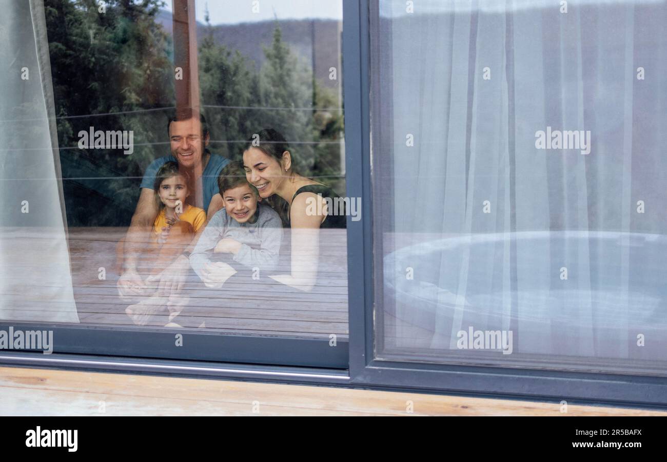 Happy young family is sitting on living room floor. Parents and ...