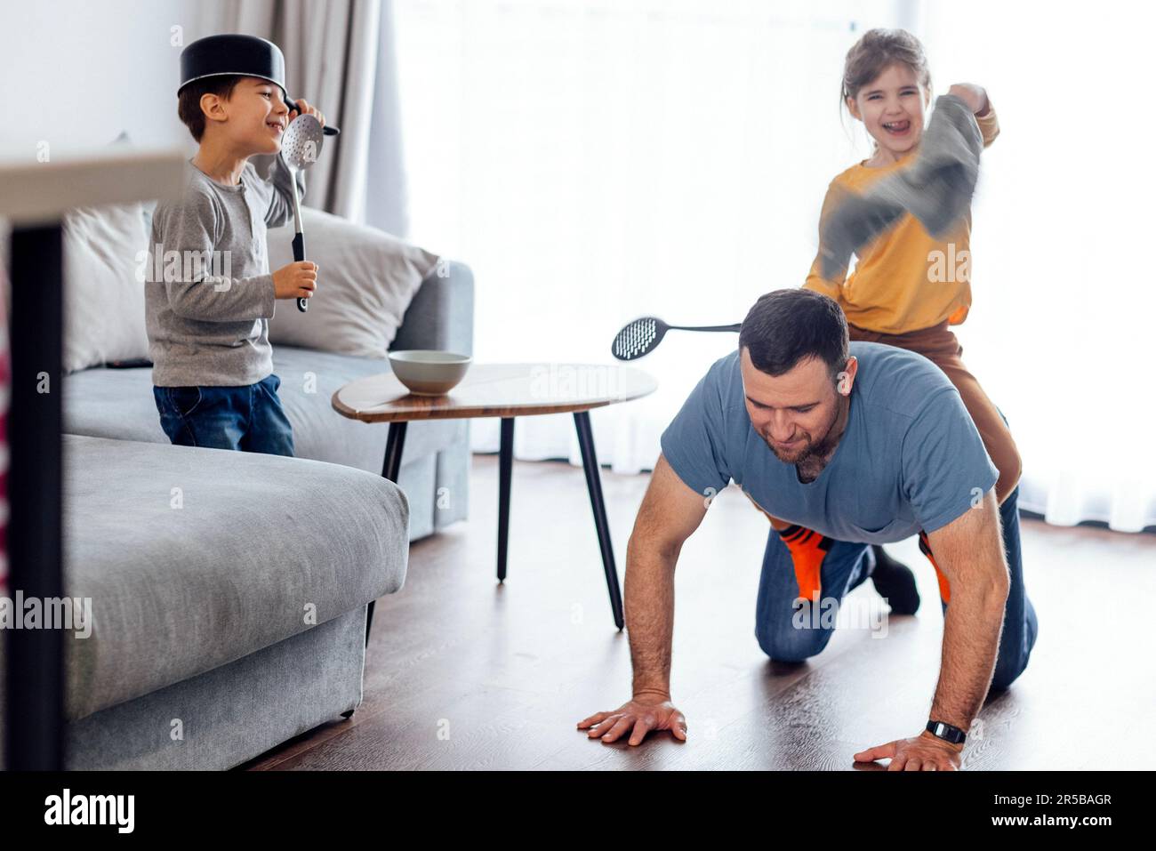 Funny cute laughing girl is riding on her dad and waving towel ...