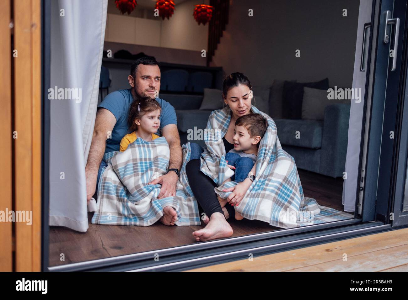Young parents and small children sit on floor of living room at home in ...